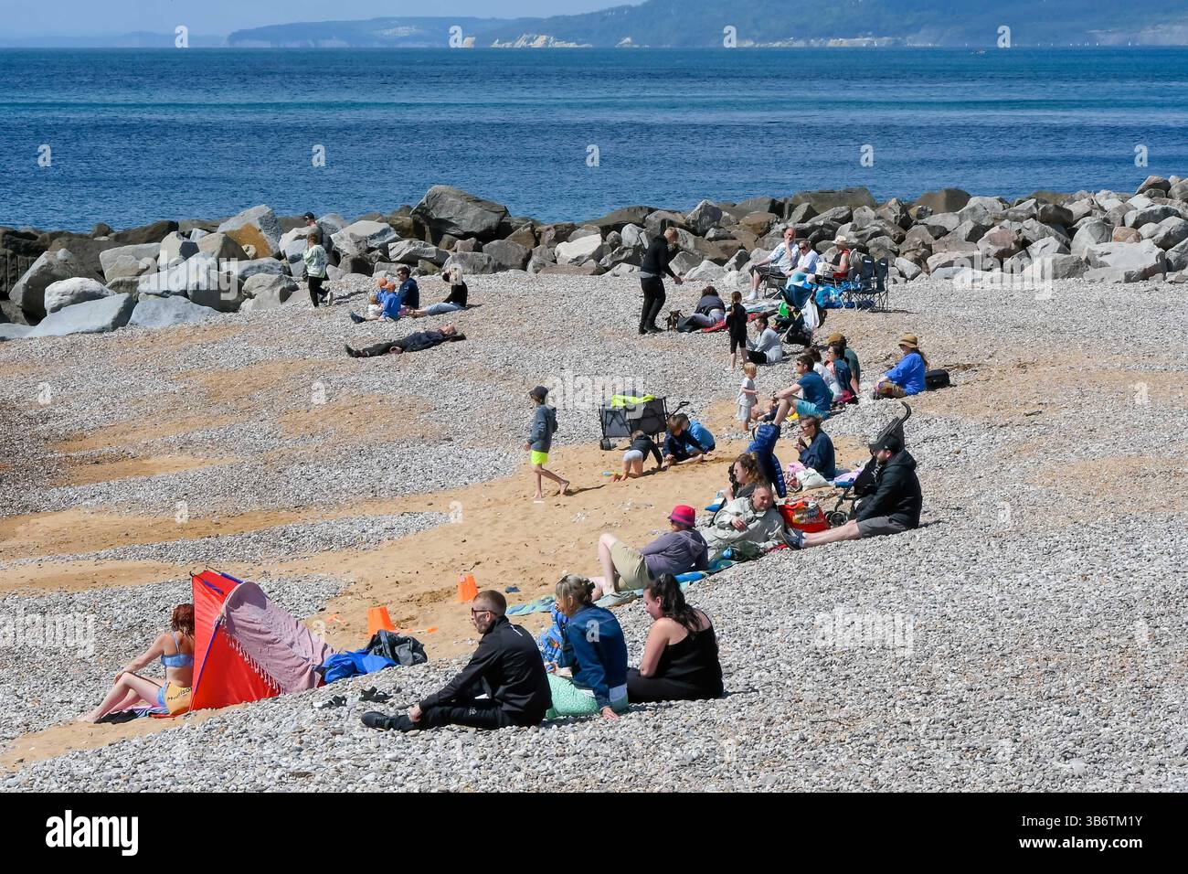West Bay, Dorset, UK. 4th May 2025. UK Weather. Beachgoers enjoying the ...