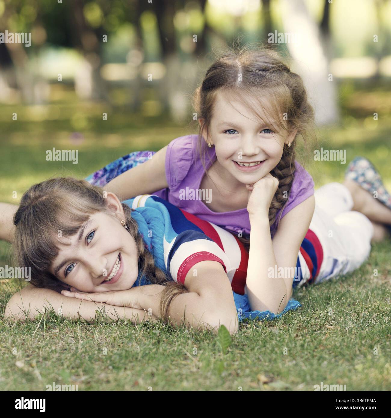 Funny girls laying on the grass Stock Photo - Alamy