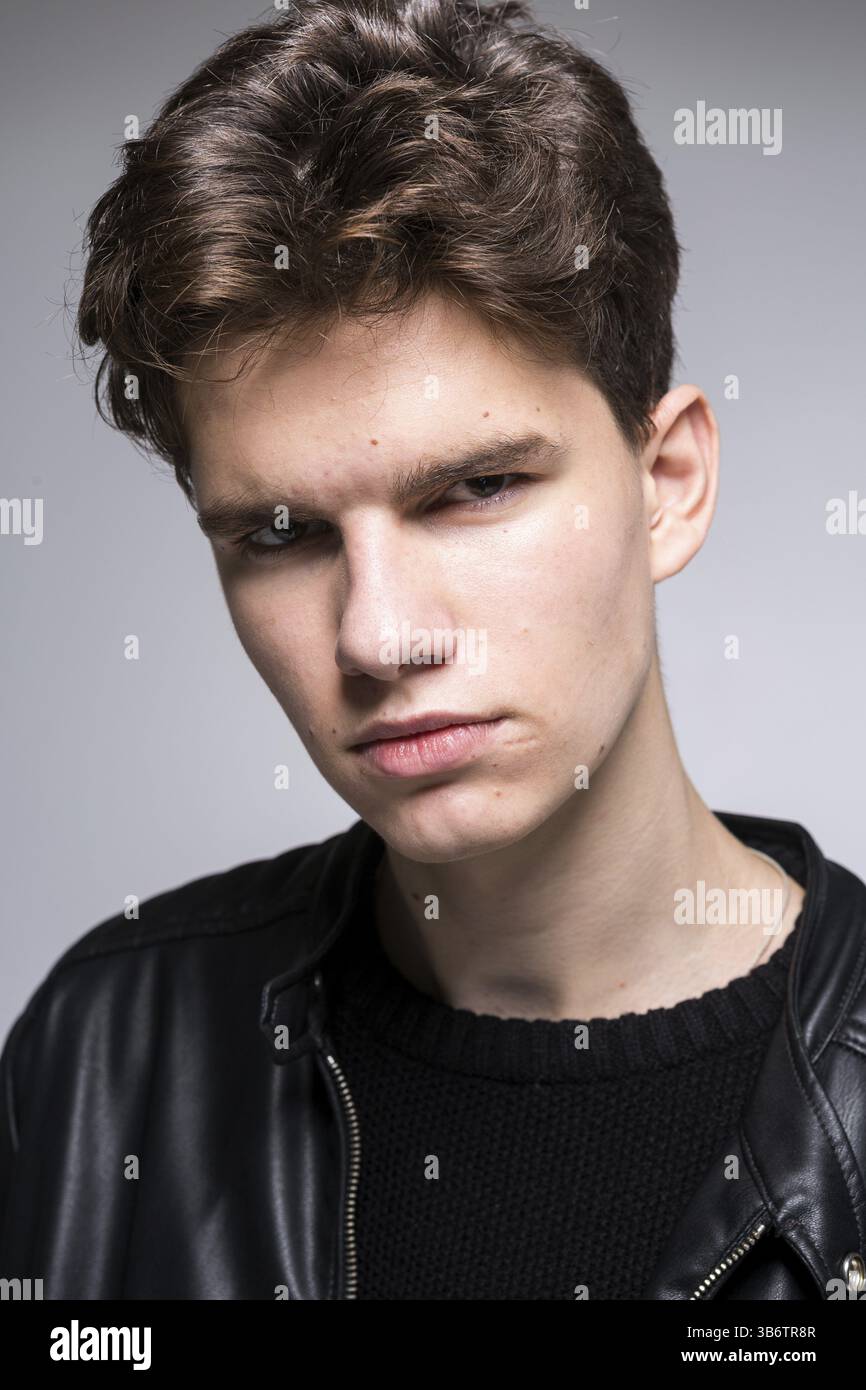Wide angle. Studio shot. Young caucasian guy model in black clothes posing in the studio ...