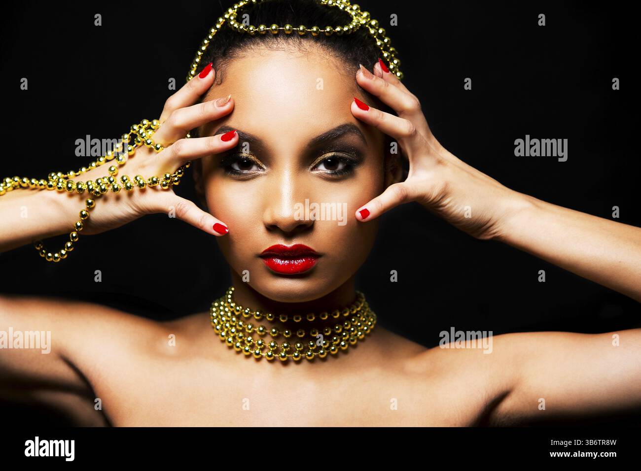 Upscale Indian woman wearing gold jewellery and red lipstick on black ...