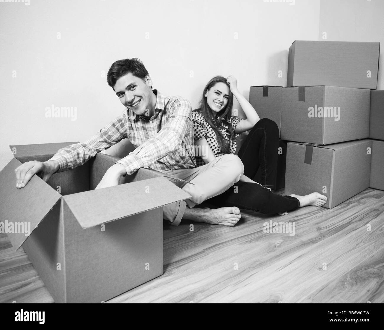 Young couple unpacking boxes in a living room Stock Photo - Alamy