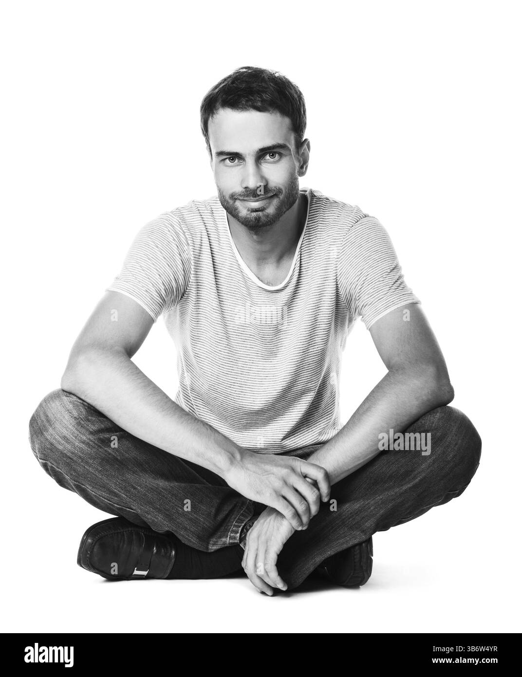 A man wearing casual jeans and t-shirt sits relaxing with his legs ...
