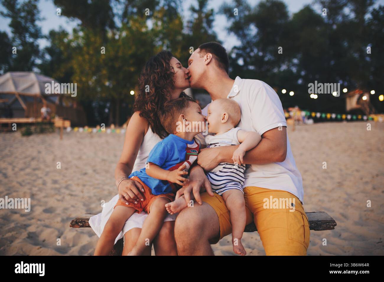 The concept of a family holiday. Young family and two sons sitting on a ...