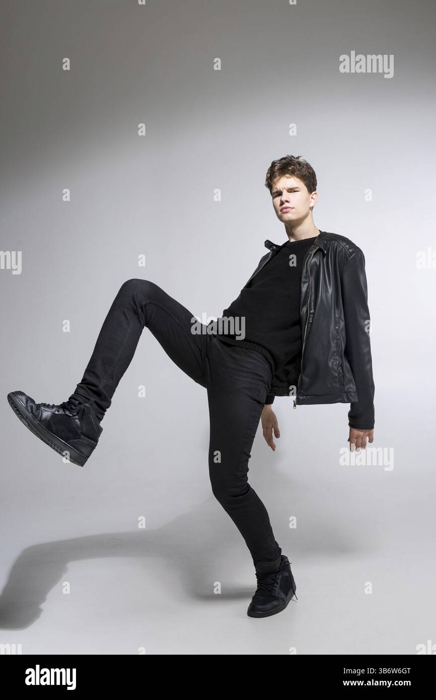 Full length portrait of young fit man in dark cloths on the white ...