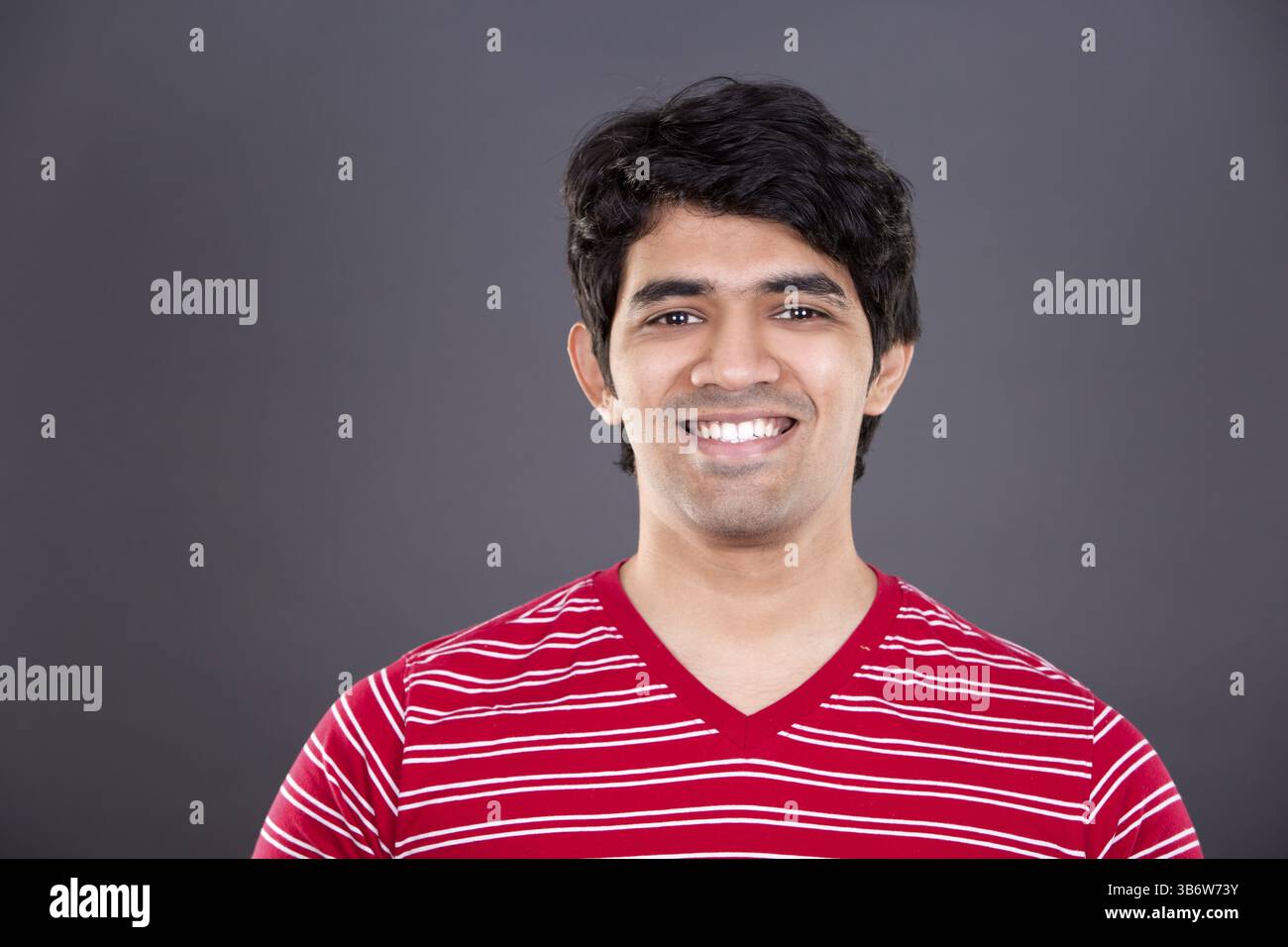 Handsome east indian man wearing red shirt on light grey background ...