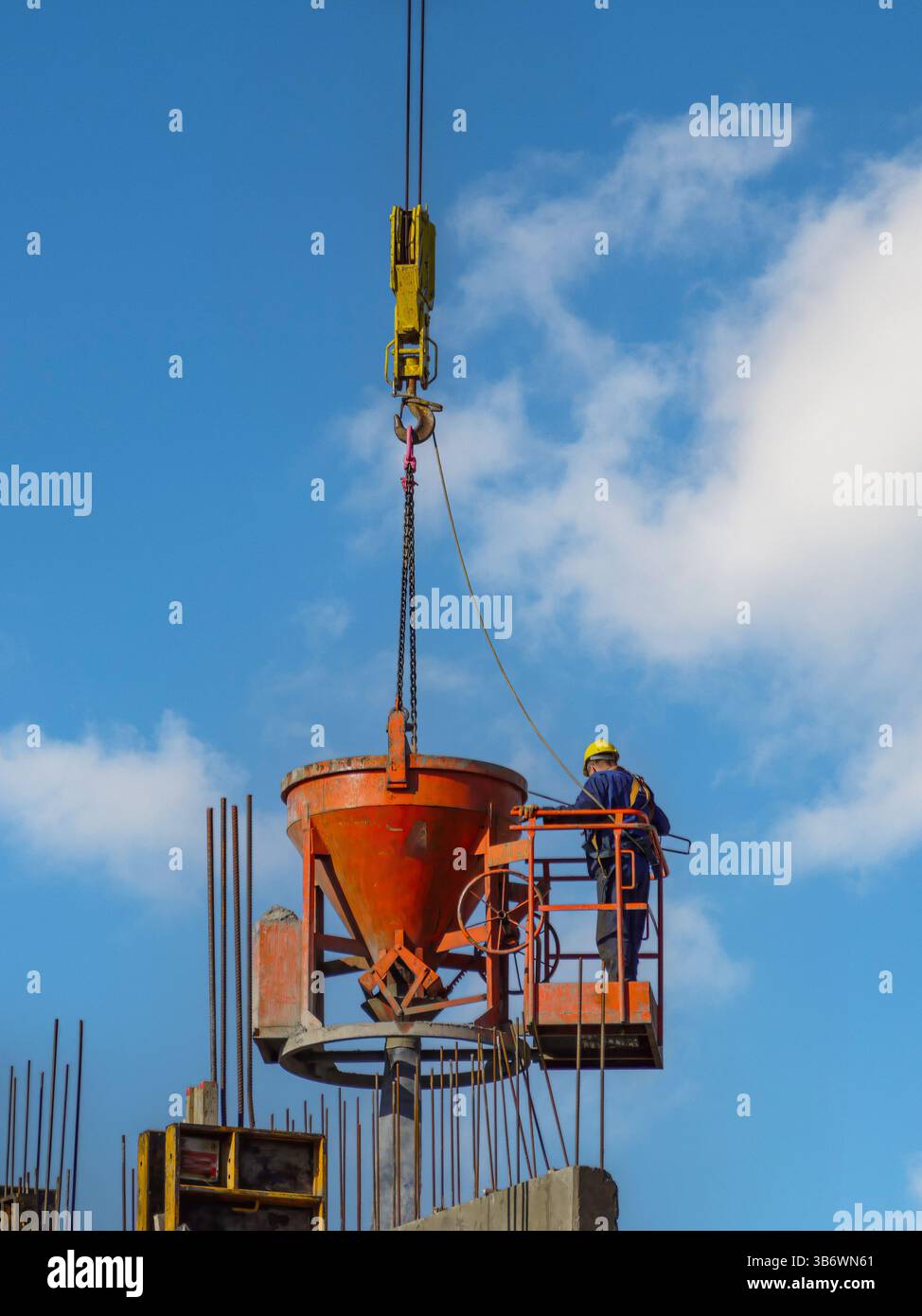 Construction worker pouring concrete mix from charging hopper platform ...