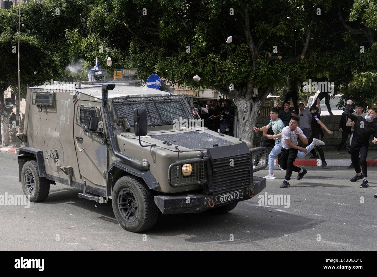 Palestinians throw stones at an Israeli security forces vehicle during ...
