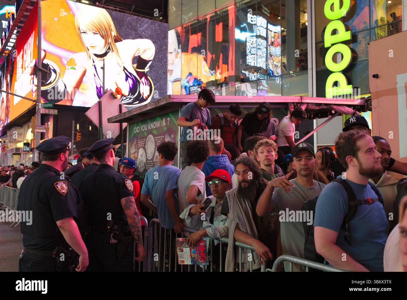 A crowd of people stands in Times Square, New York City, near a ...