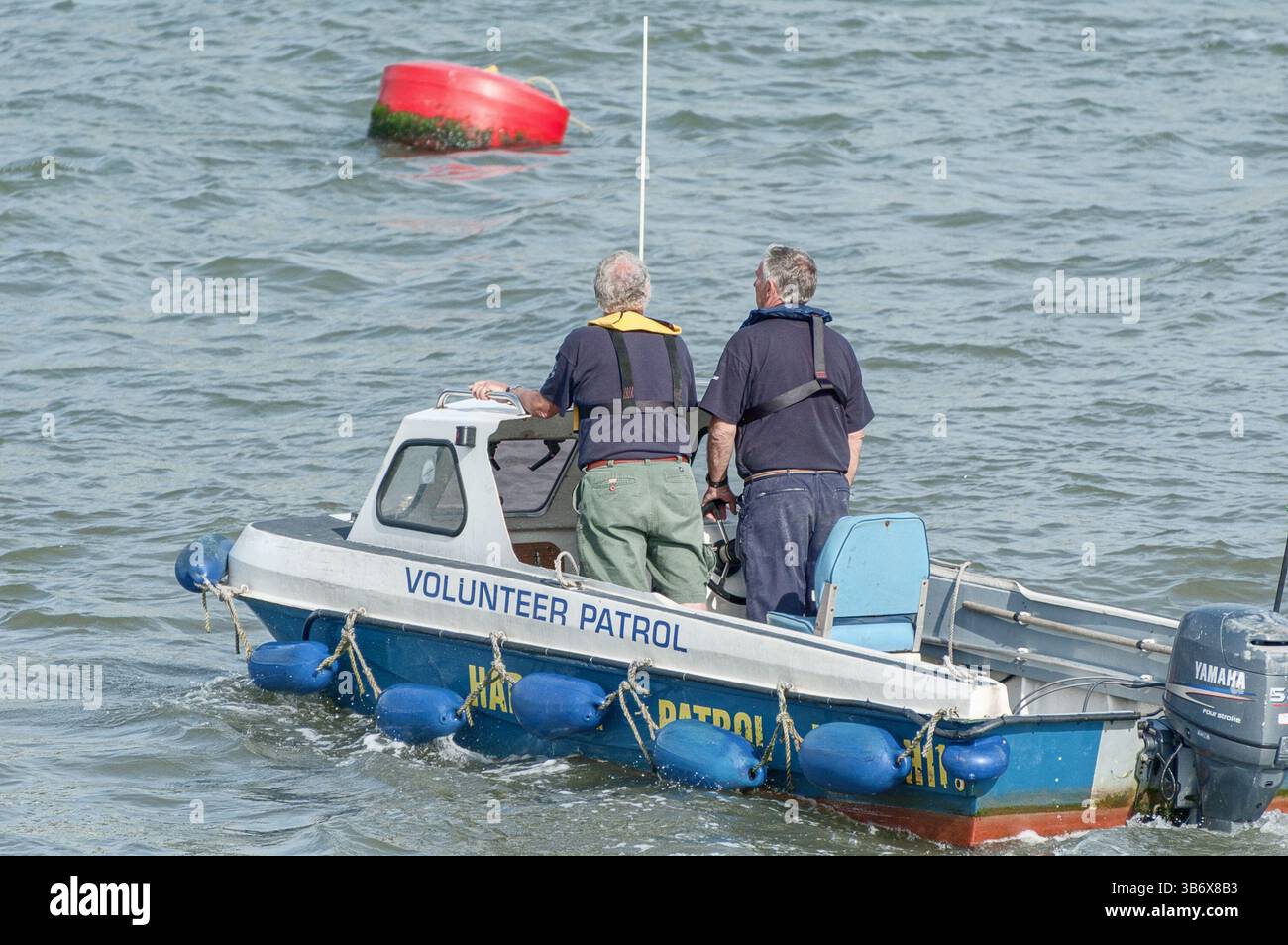 Two men in volunteer harbour patrol boat sail in Dartmouth estuary ...