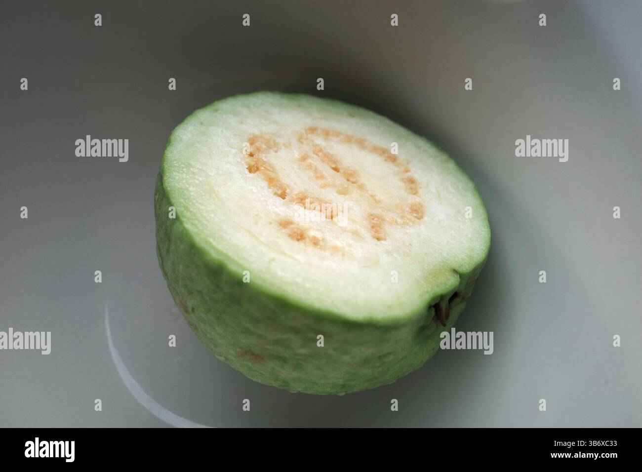 Top down view of half of a guava in a white container Stock Photo - Alamy
