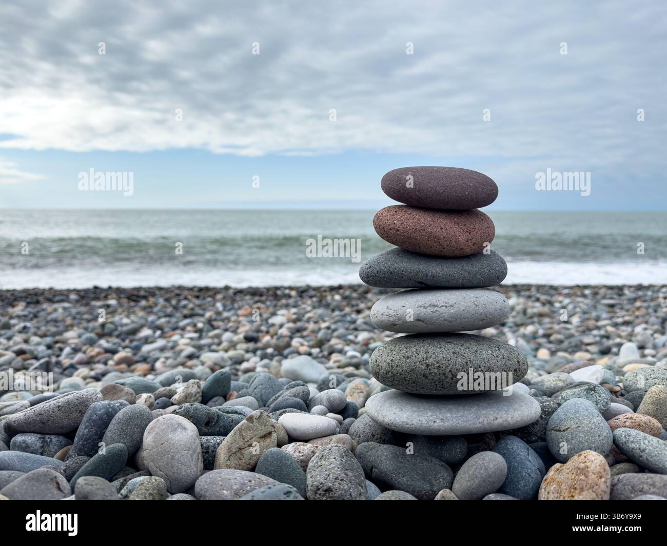 Balanced stack of smooth sea stones on a pebble beach with ocean waves ...