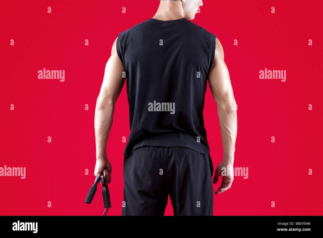 Aerobic workout. Back view of strong young man standing with skipping ...