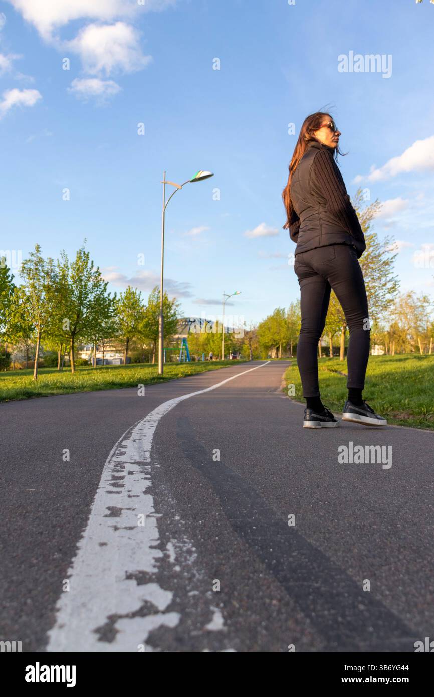Asphalt surface of the jogging trail with painted dividing lane. Woman ...