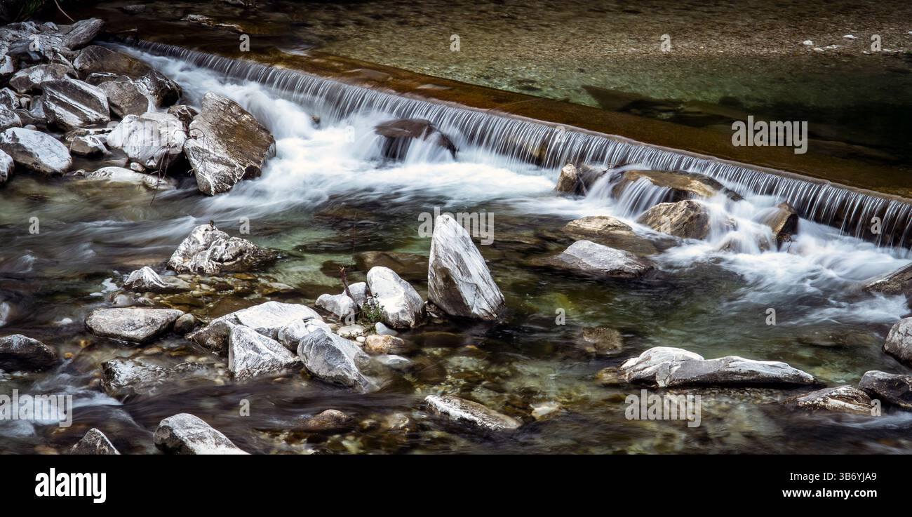 A serene river scene featuring flowing water over rocks, creating a ...