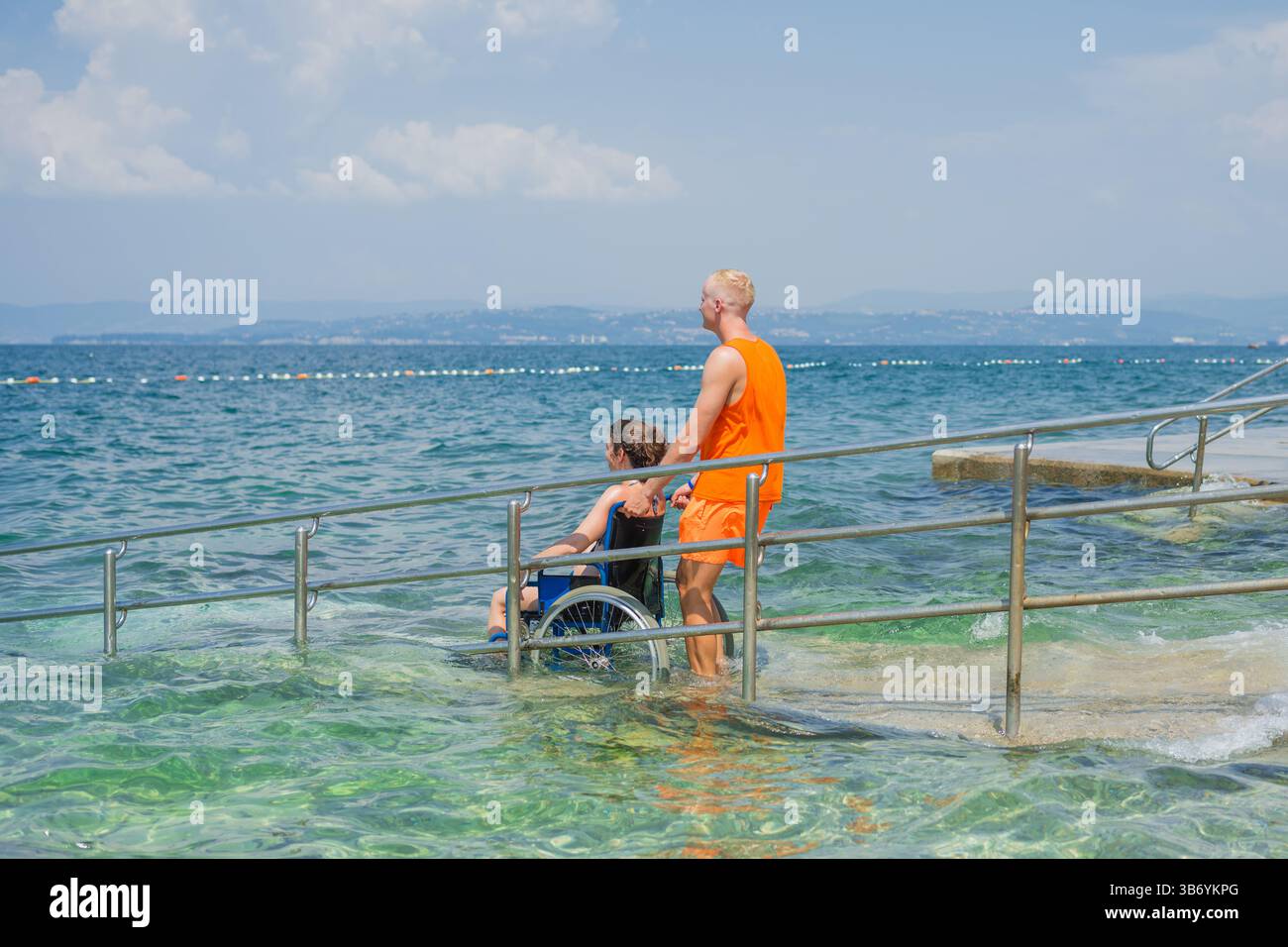 Male assistant pushing a woman with disability in a wheelchair into the ...