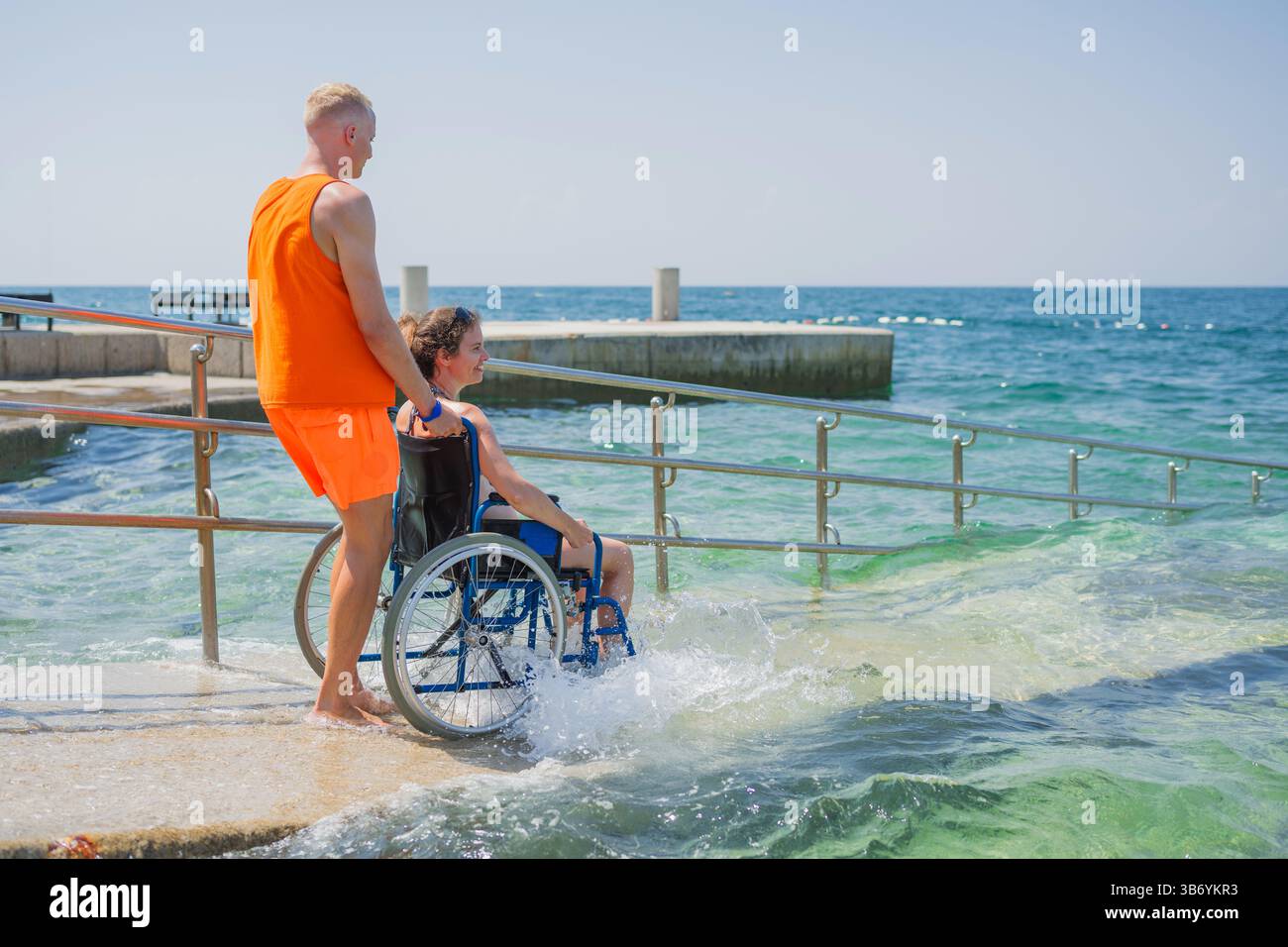 Woman with disability, entering the sea water with the help of a ...