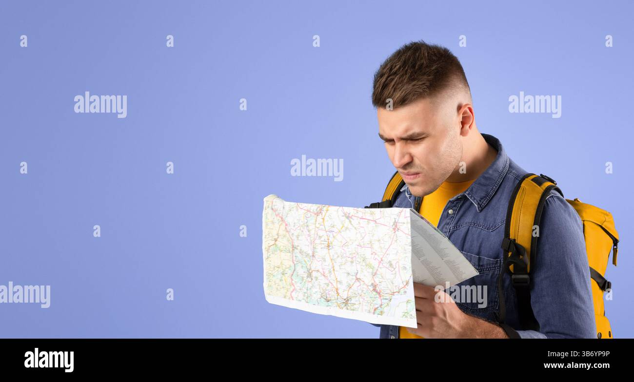 Puzzled young guy with tourist backpack and map over blue studio ...