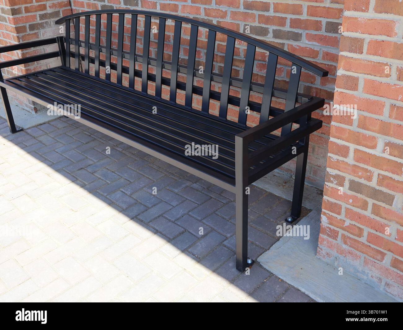 black metal benches with slatted seats and backrests anchored to brick ...