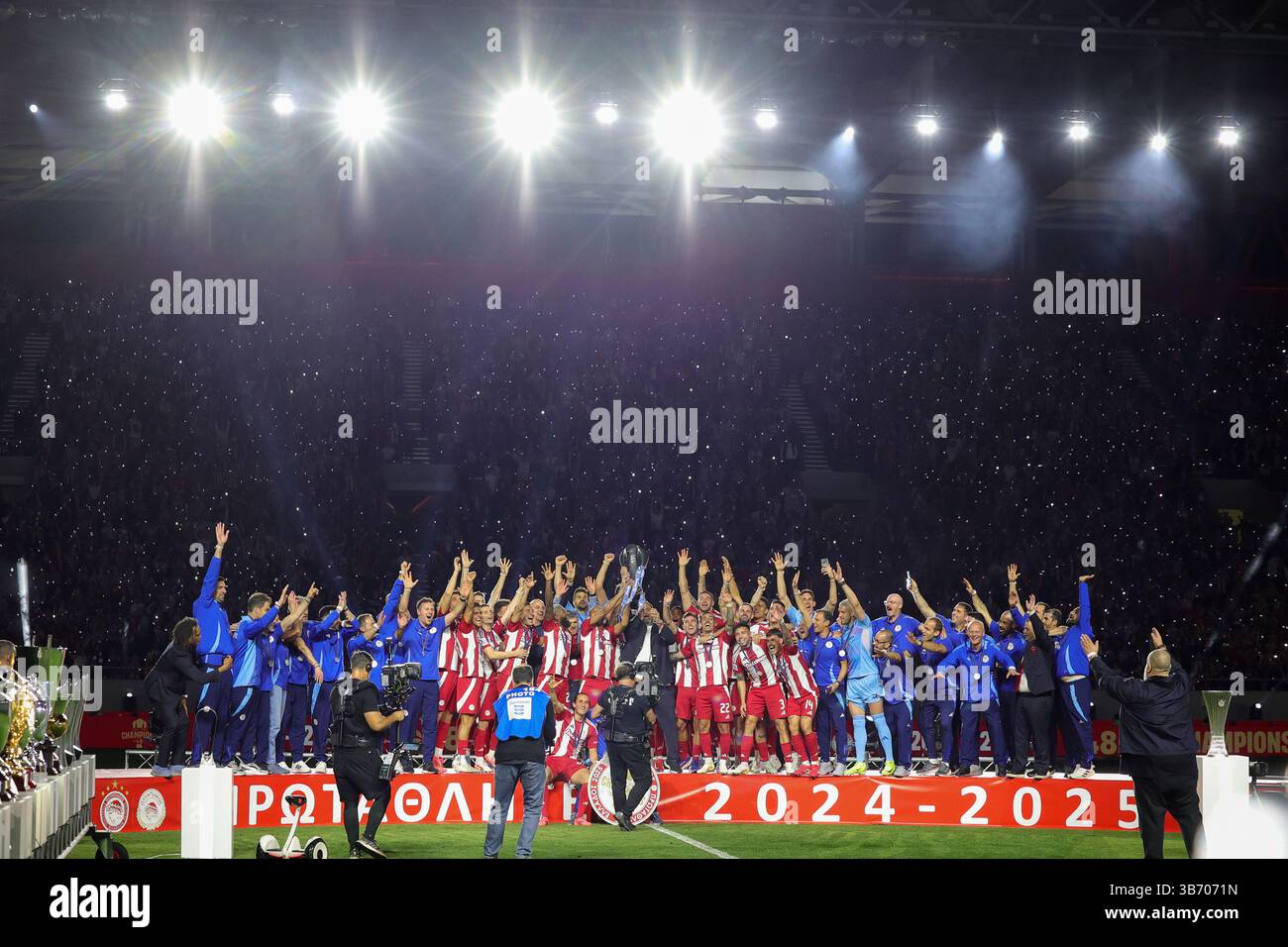 Olympiacos club owner Evangelos Marinakis, center, raises the trophy ...