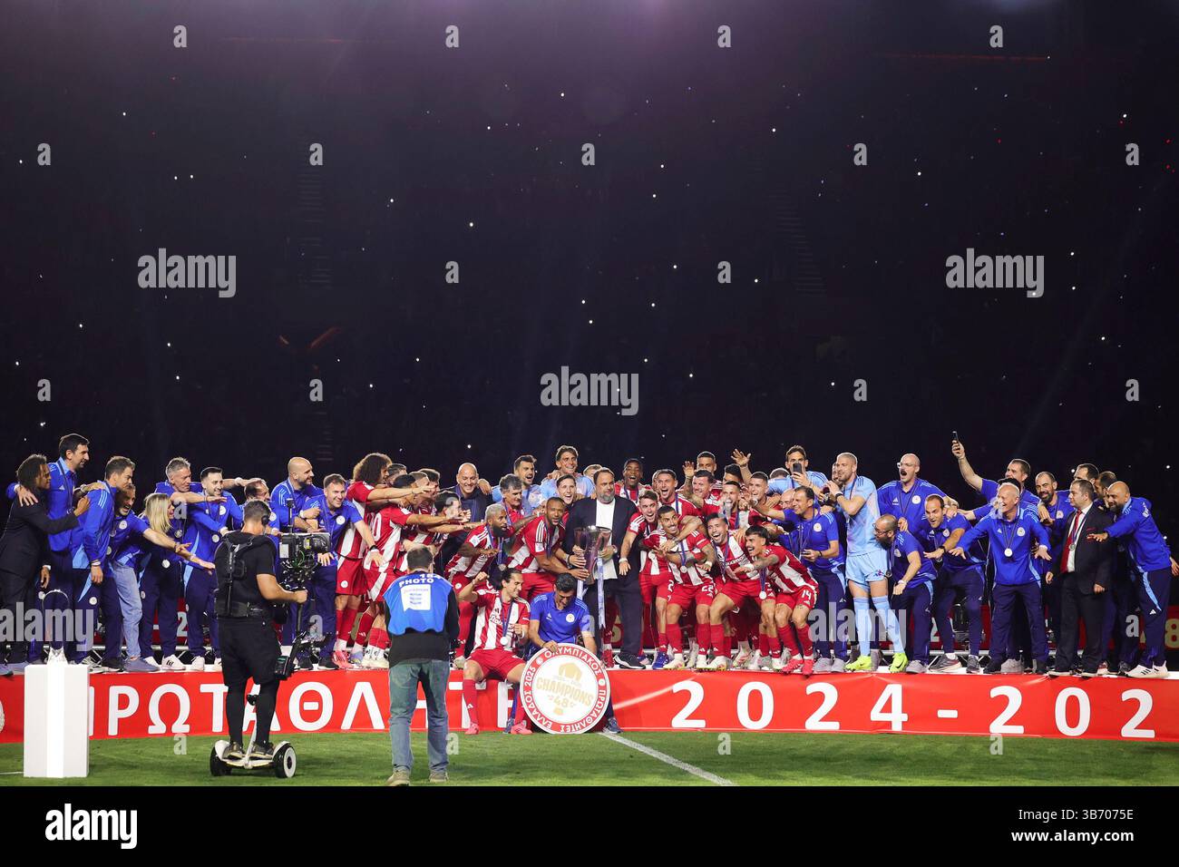 Olympiacos club owner Evangelos Marinakis, center, holds the trophy ...