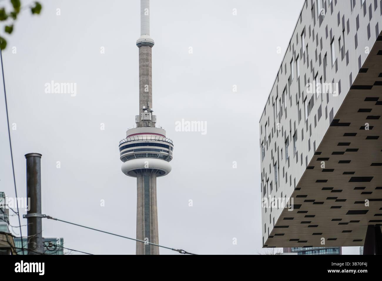CN Tower detail with modern building facade under grey sky in Toronto ...