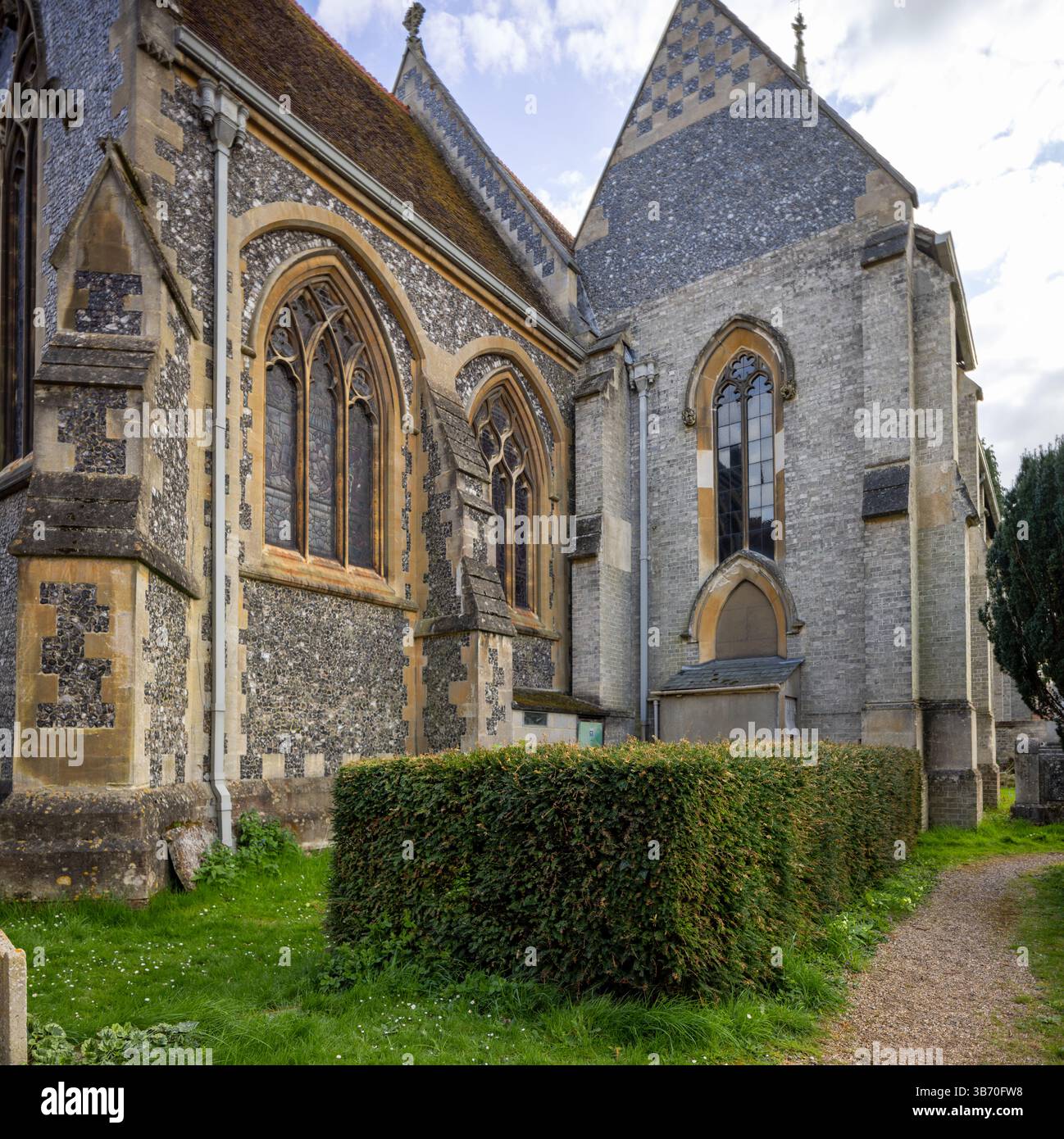 Side view of flint church showing stained glass and wildflowers Stock ...