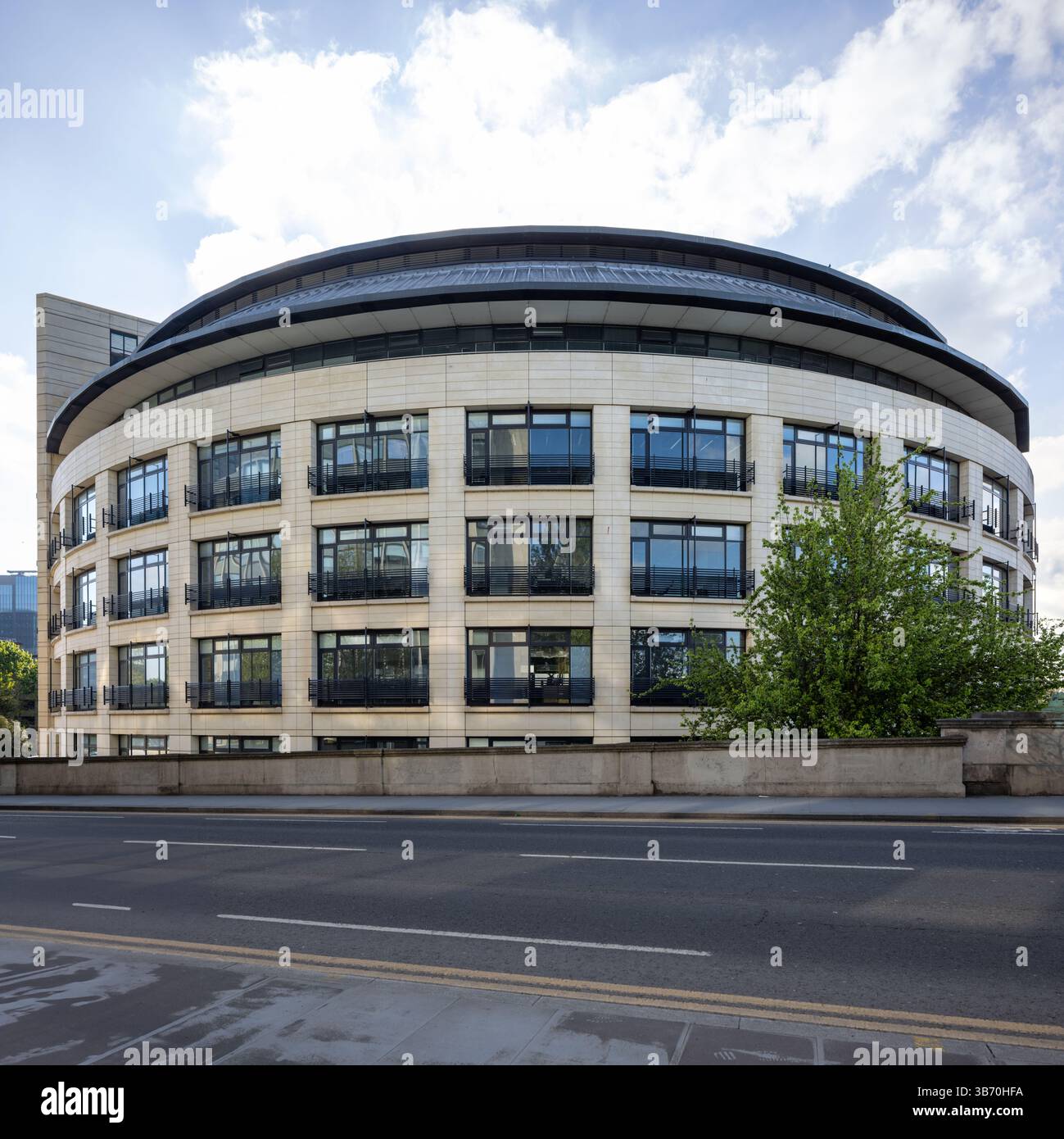 Street-level view of a large, curved modern office building with stone ...