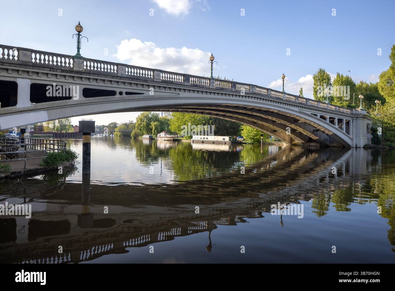 Wide concrete arch bridge spanning a river, reflecting in the water ...