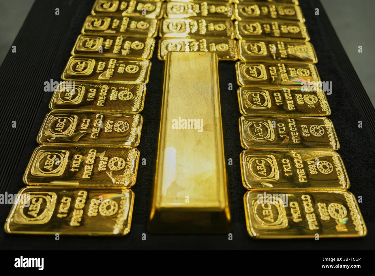 A 12.441 kg gold bar sits amongst one kilogram gold cast bars with 99. ...