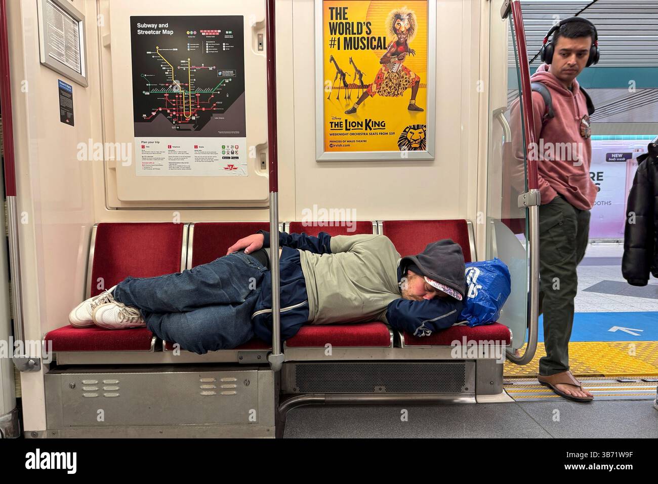 A homeless man sleeps on the seats at subway in Toronto, Canada, Sunday ...