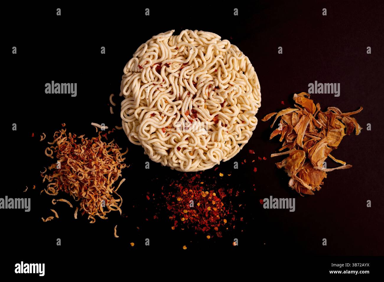 Top view of uncooked ramen noodles formed in circle with dried onion ...