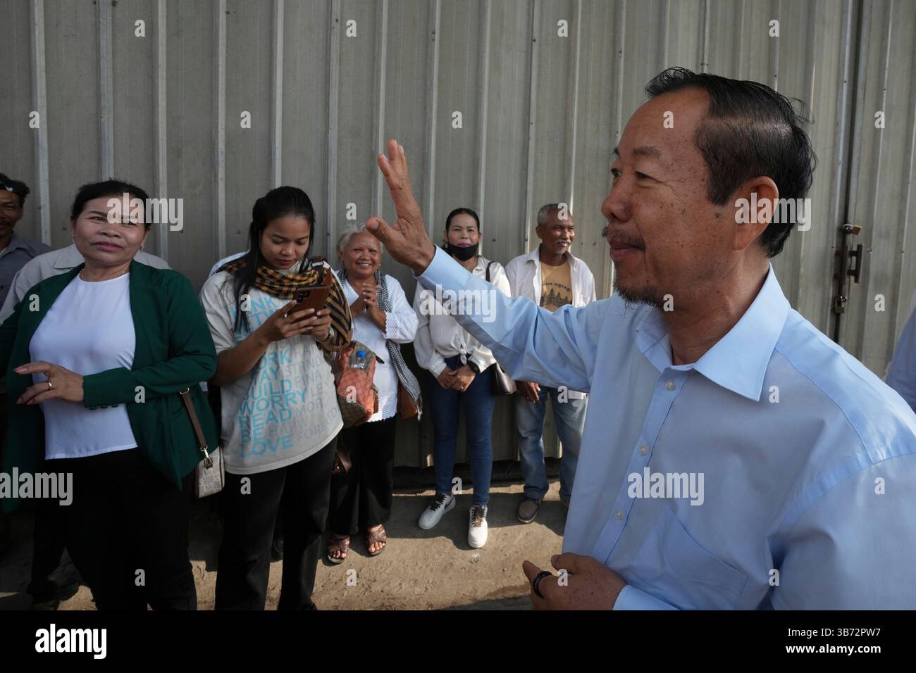 Cambodian prominent opposition politician Rong Chhun, right, waves to his supporters near the ...