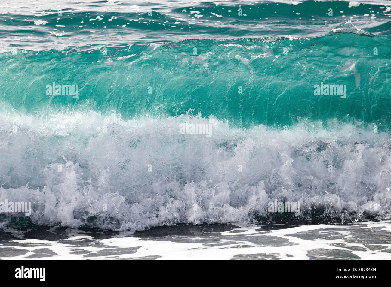 Surf of the sea wave with clear water on the coast with small stones ...