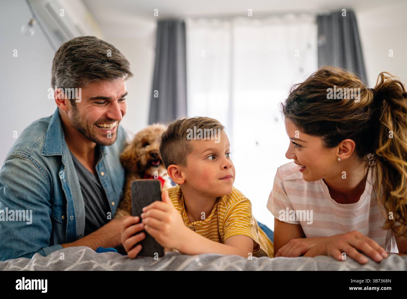 Happy family and kid having fun with smartphone, digital gadget at home ...