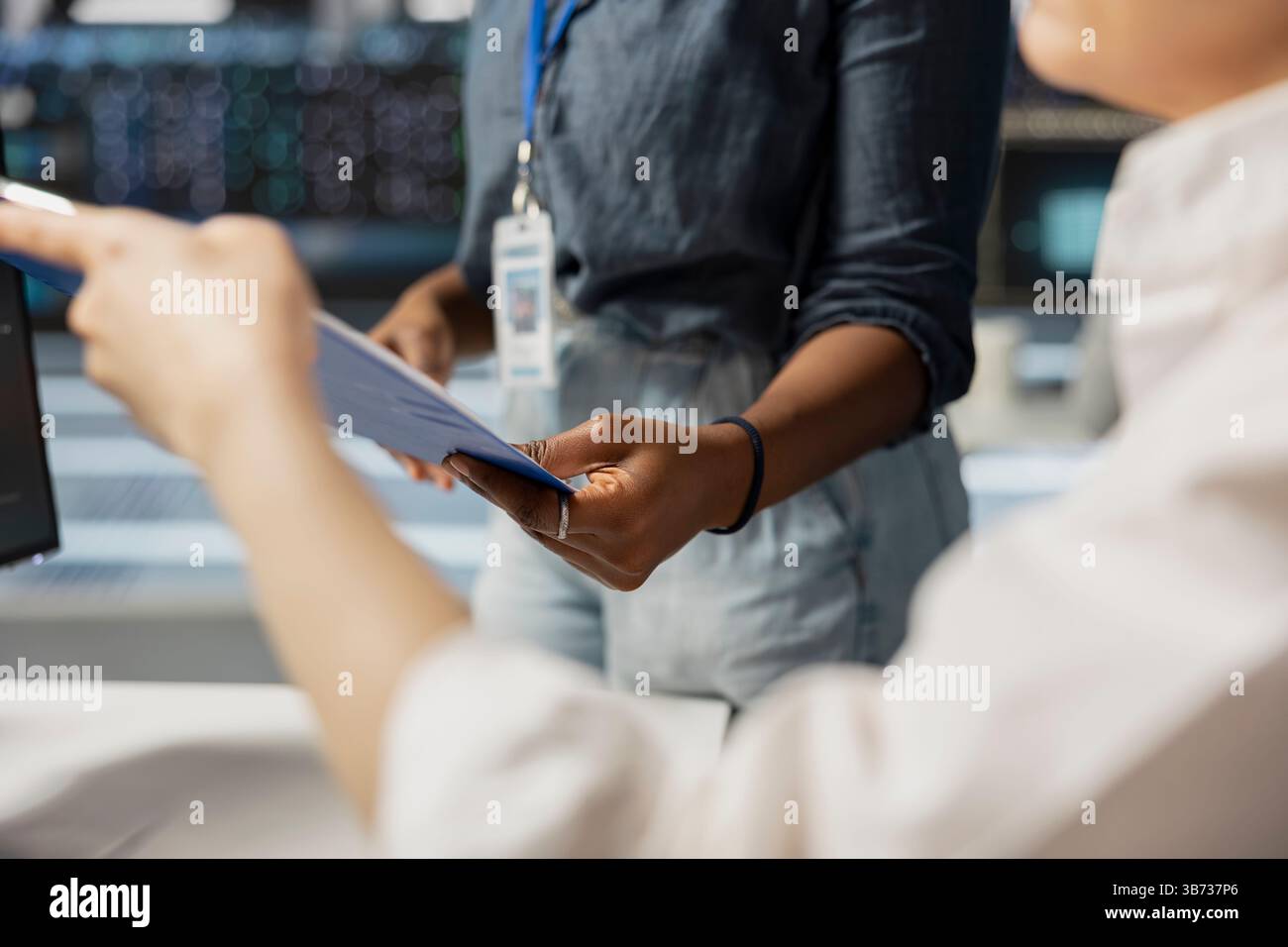 Close up of server room employees reviewing documentation on clipboard ...