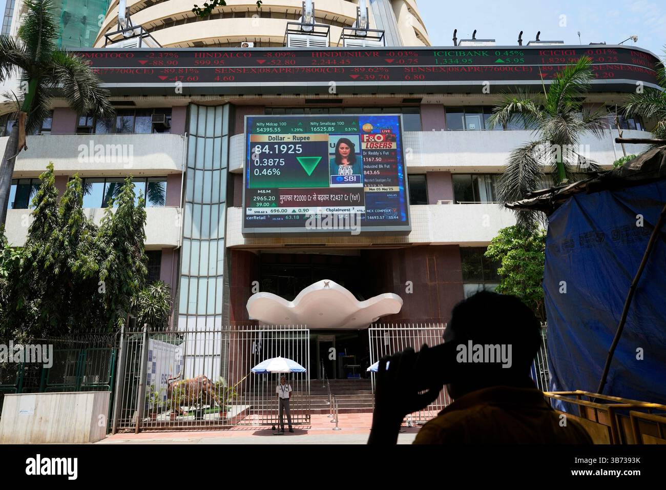 A security guard stands in front of a live screen on the facade of the ...