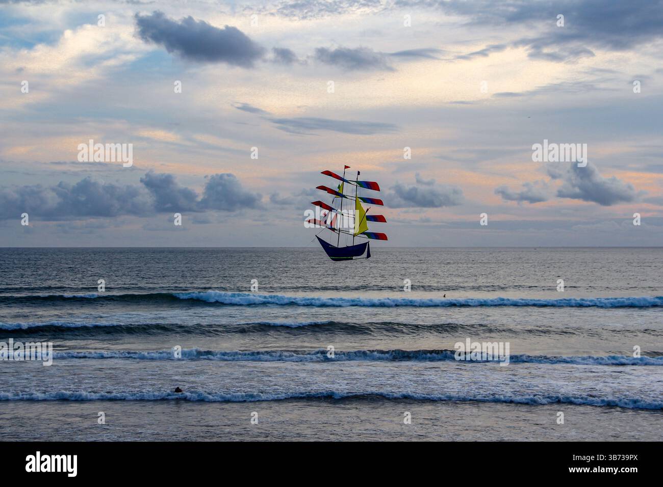 Colorful parasail above gentle Bali waves at sunset, a perfect scene ...