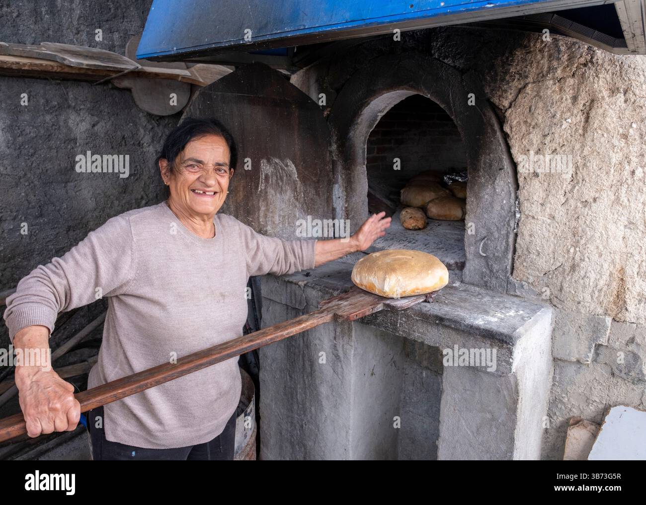 Senior woman making bread in a traditional bread oven, Korucam ...