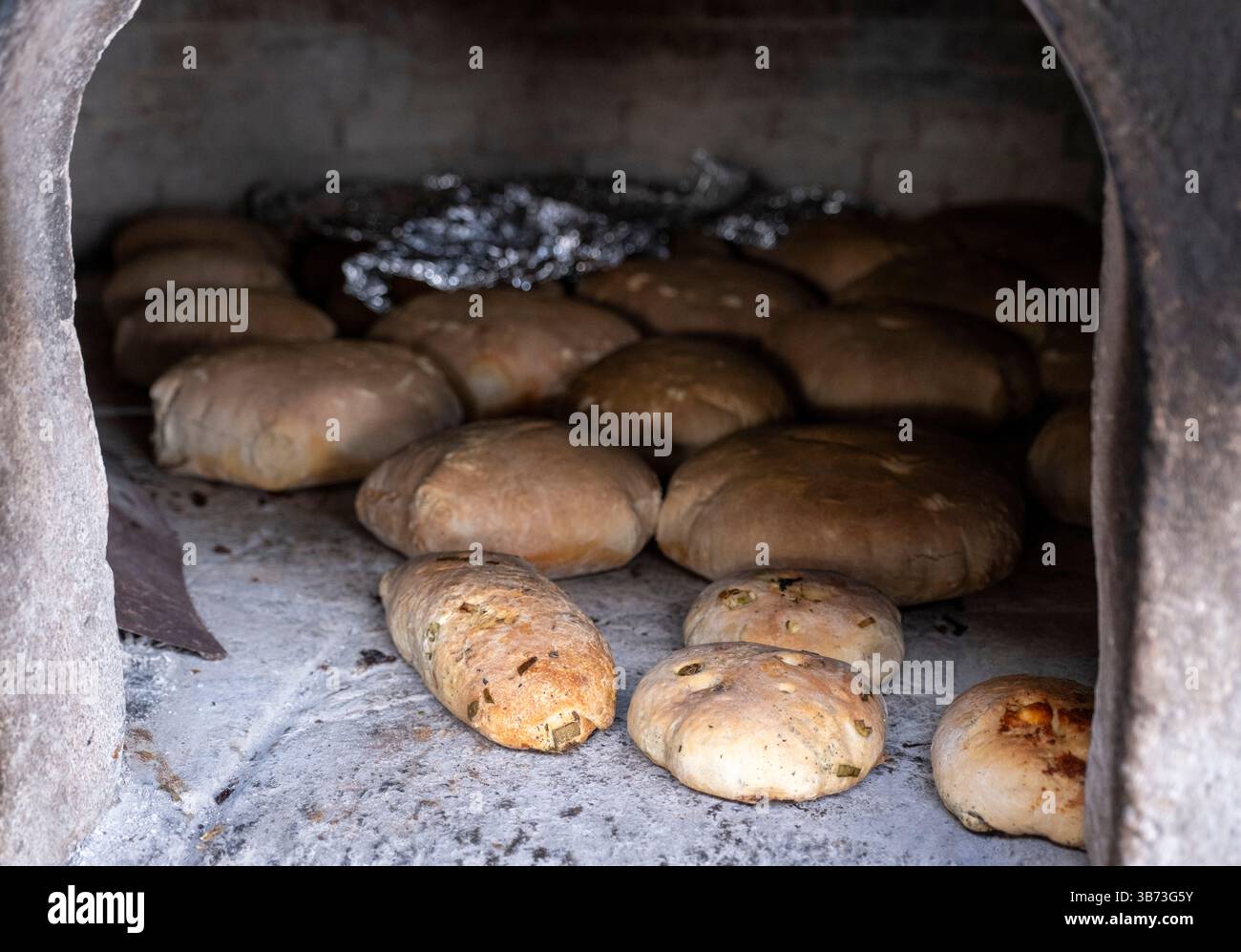 Senior woman making bread in a traditional bread oven, Korucam (Kormakiti) Maronite village ...