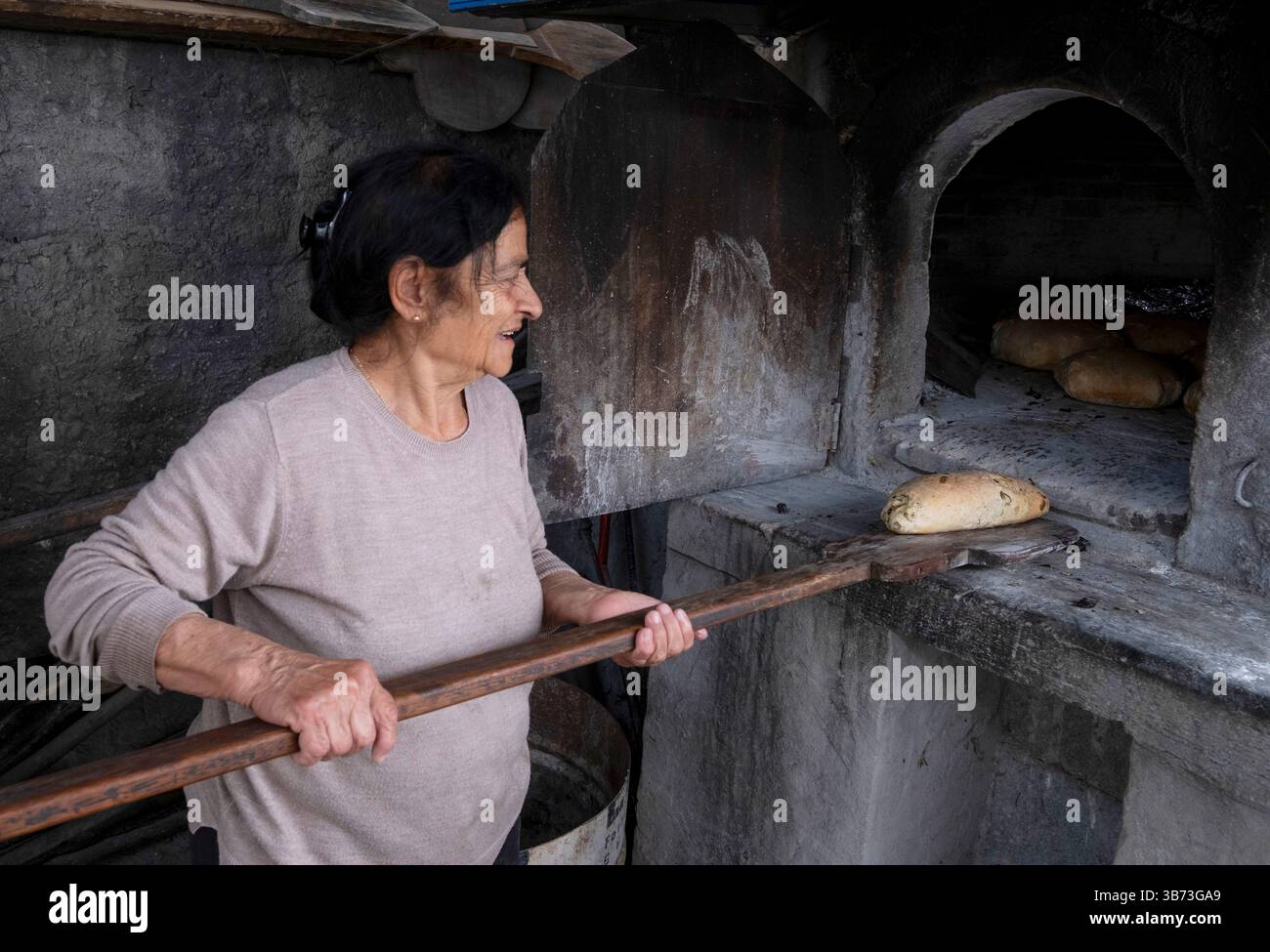 Senior woman making bread in a traditional bread oven, Korucam ...