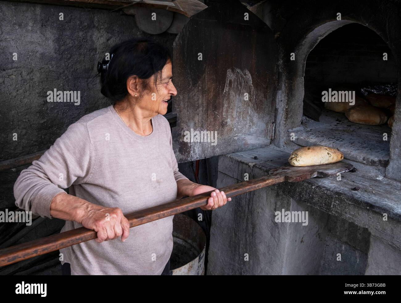 Senior woman making bread in a traditional bread oven, Korucam ...