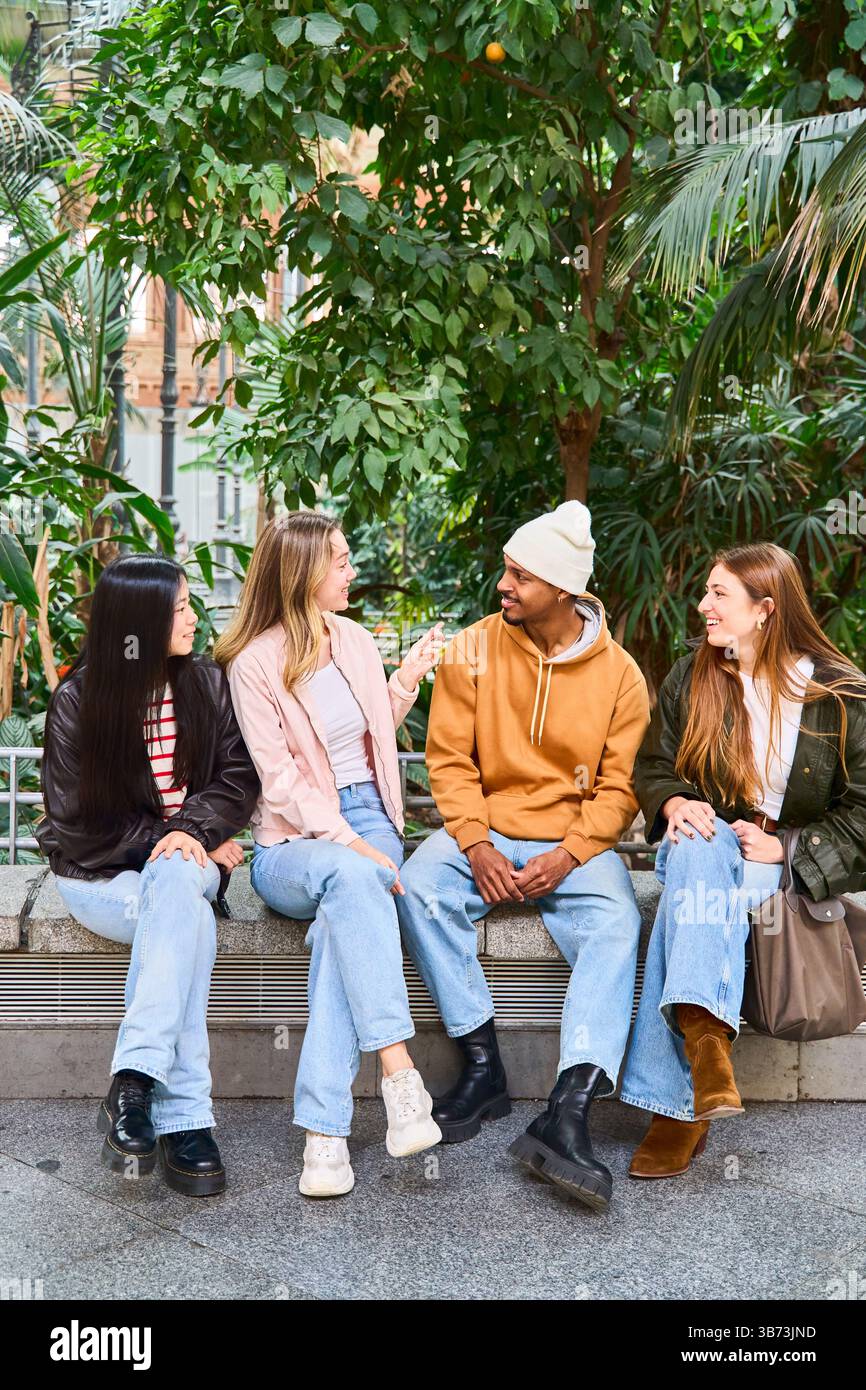 Four diverse university students enjoying a conversation together while ...