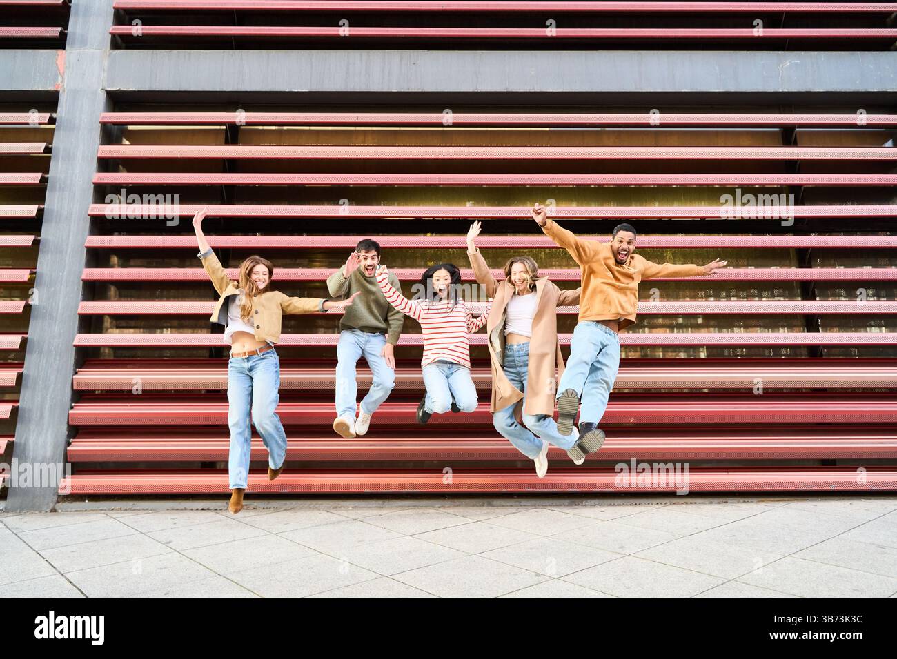 Six cheerful young multiethnic students are jumping together in front ...