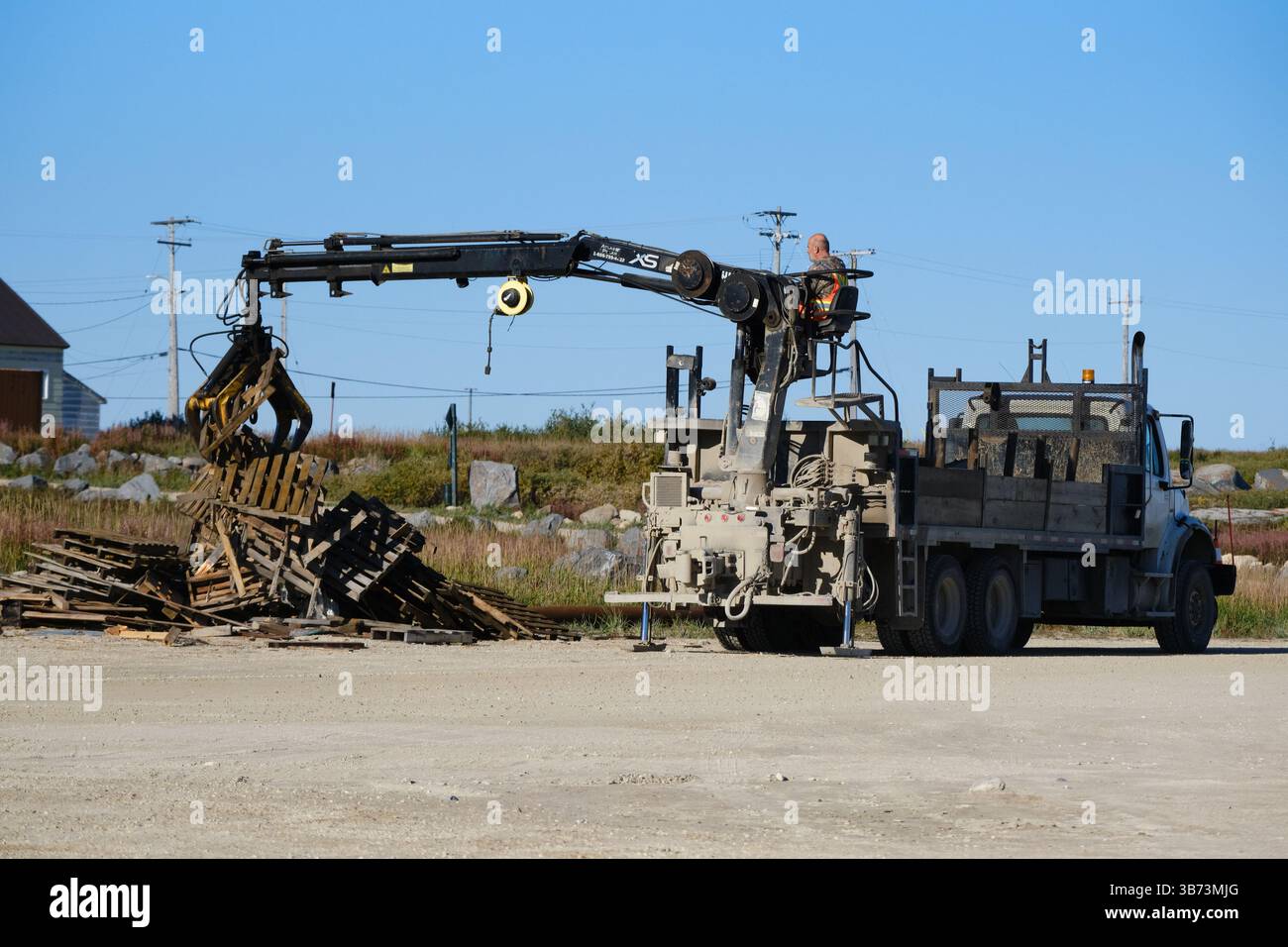 Crane of truck picking up wood debris on dirt road Stock Photo - Alamy