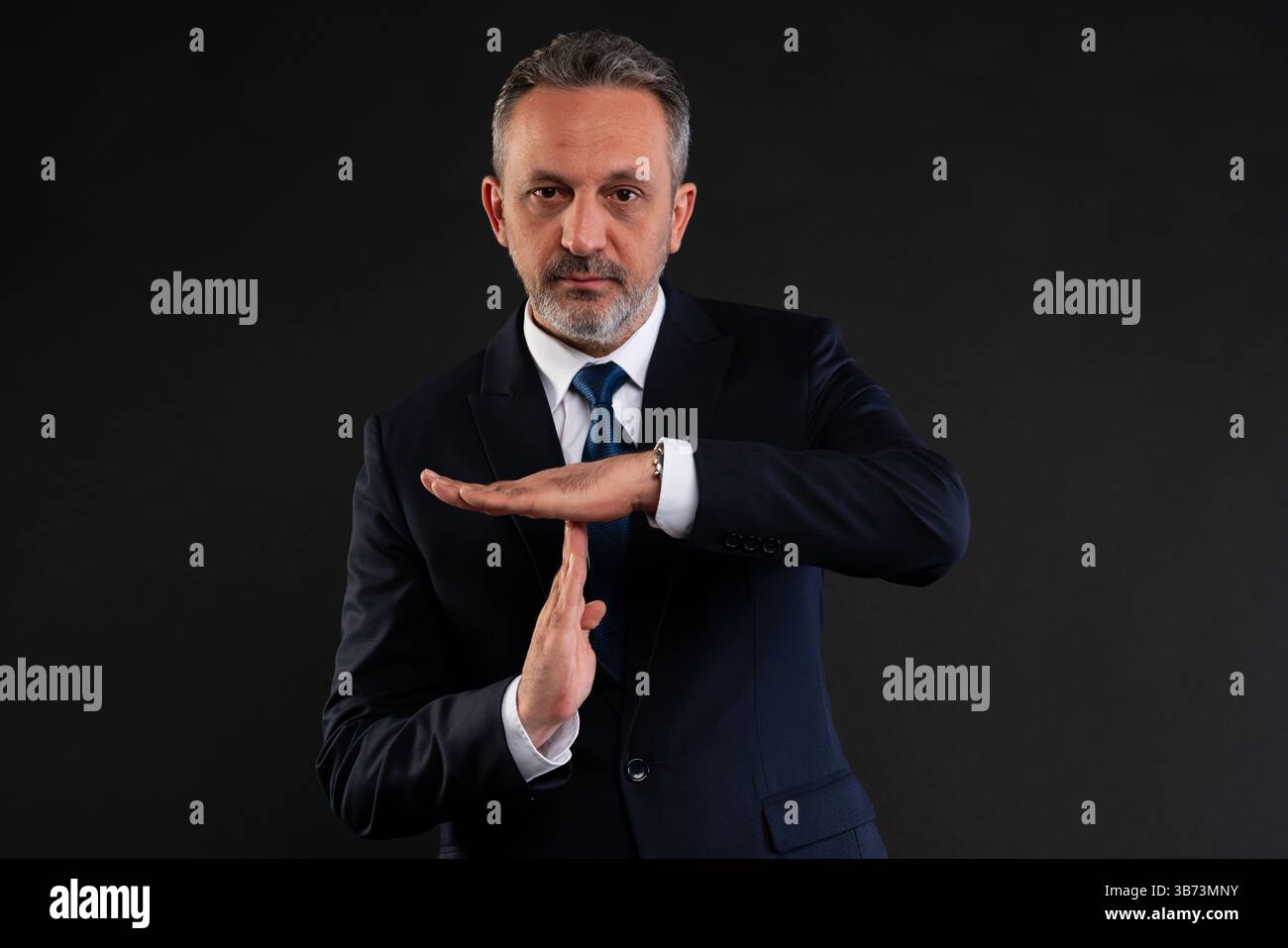 Serious businessman in suit showing time out hand gesture, indicating a ...