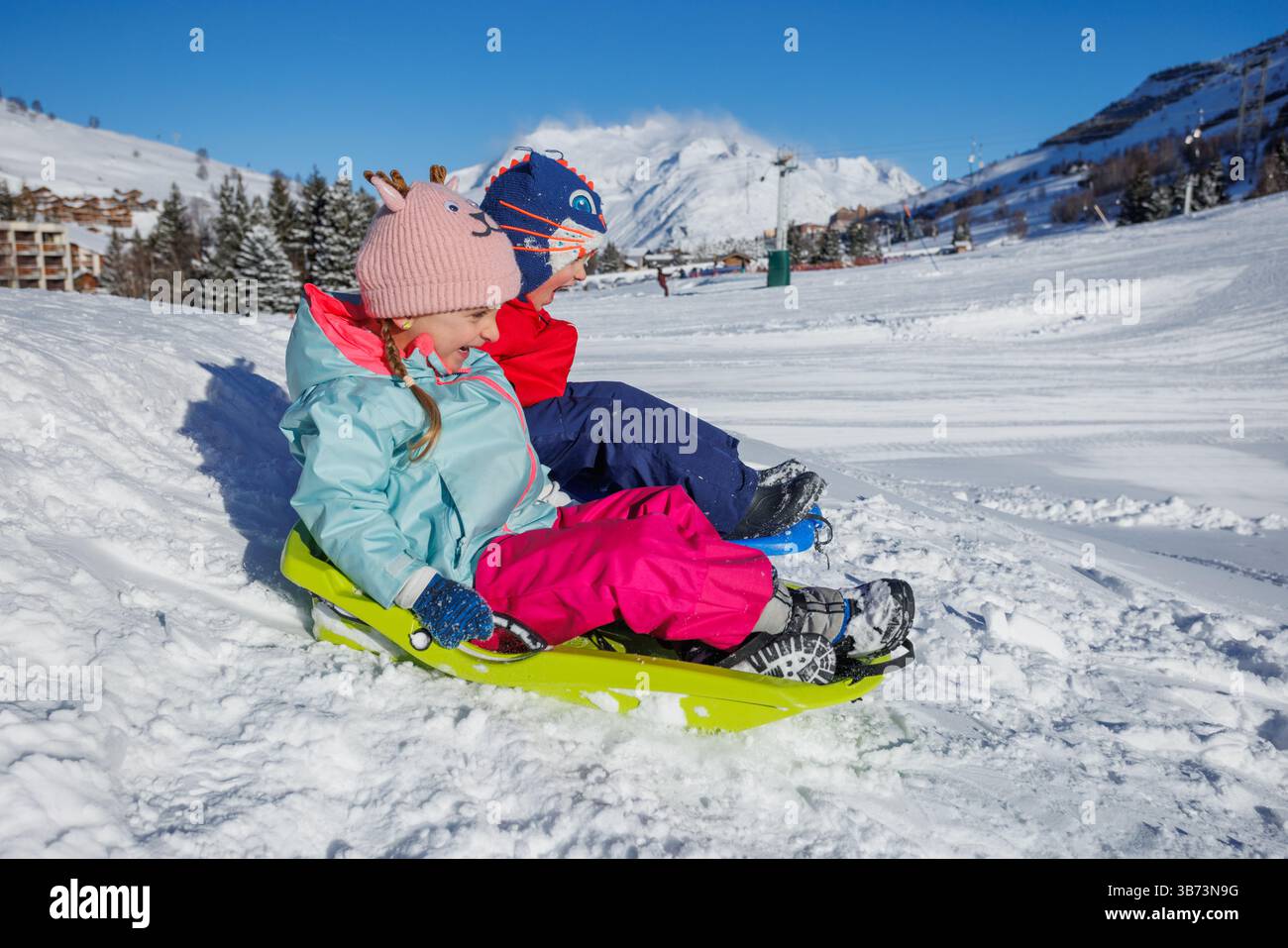 Boy and girl ride on toboggans down slope at mountains resort Stock ...