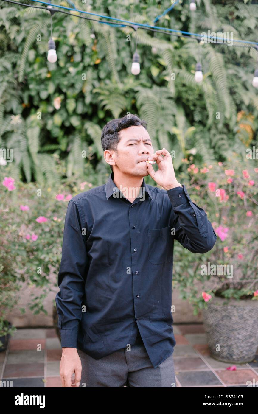 A contemplative man enjoys a cigarette outside. He is relax smoking in ...
