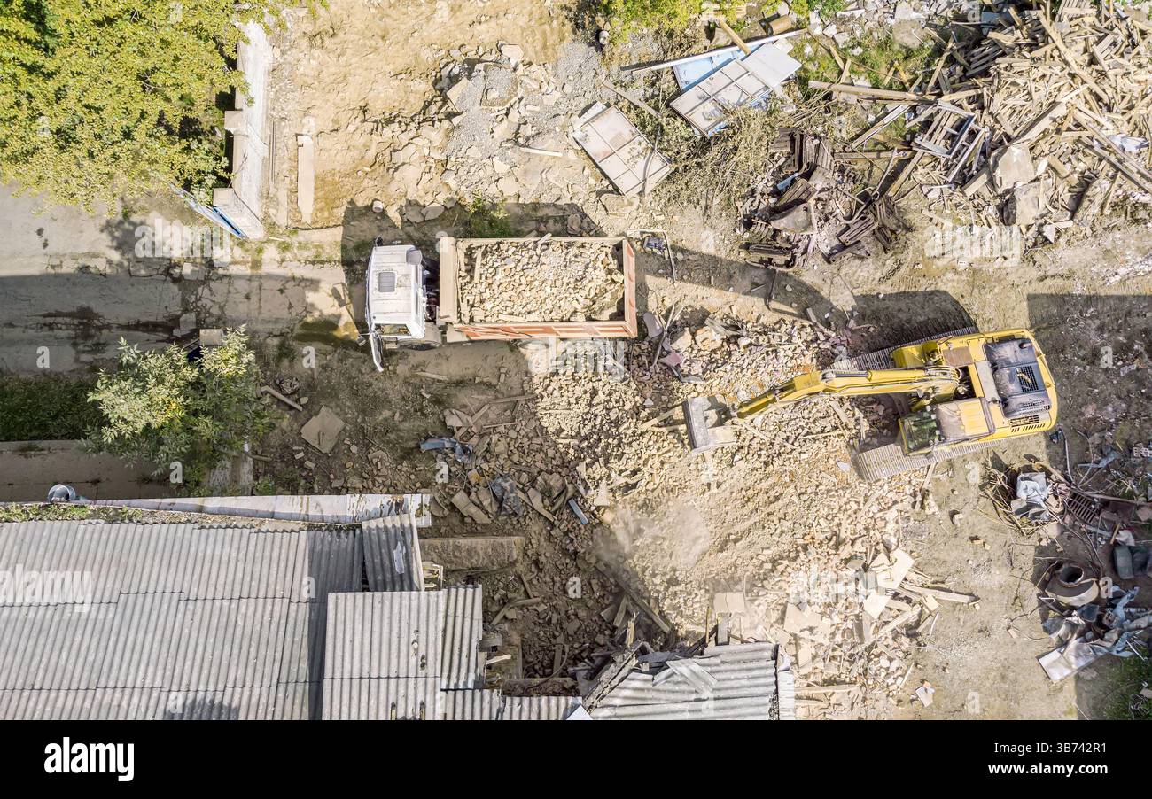 excavator loading a truck with construction debris after demolishing ...
