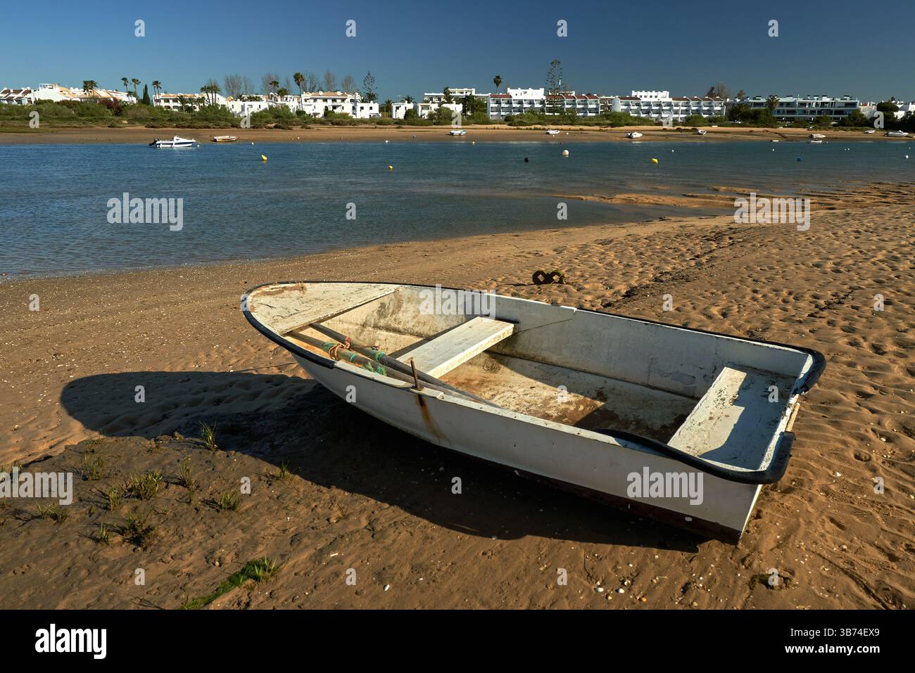 A boat sits by the Canal de Tavira between Praia da Ilha de Cabanas and ...