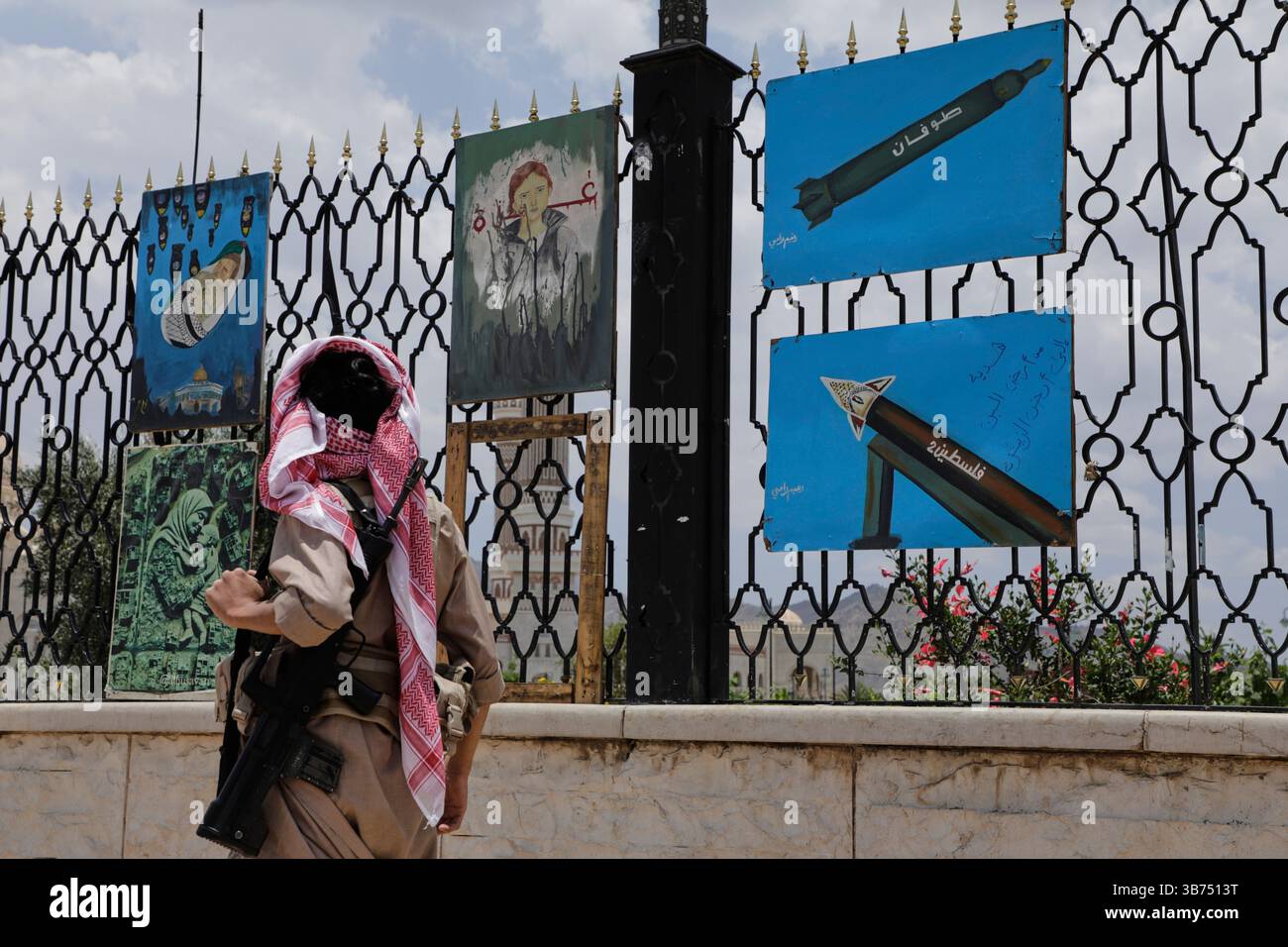 A Yemeni gunman walks past paintings depicting rockets and scenes in solidarity with Gaza ...